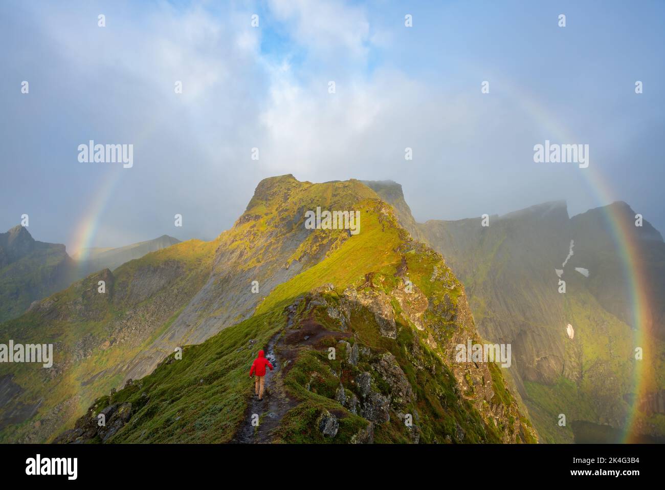 Man climbing towards a rainbow in the Lofoten Islands, Norway Stock ...