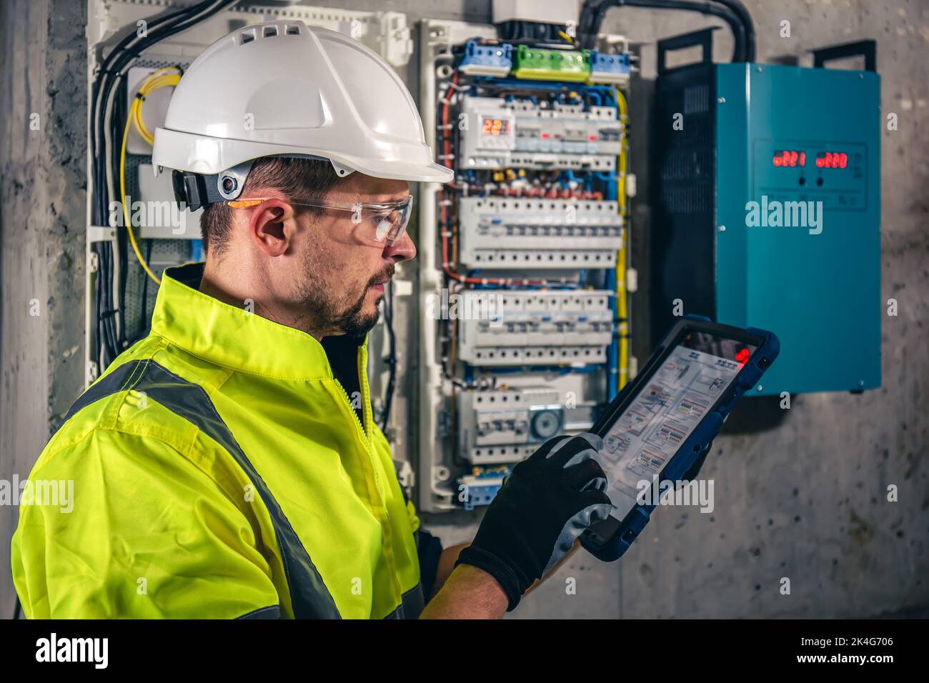 Man, an electrical technician working in a switchboard with fuses, uses ...