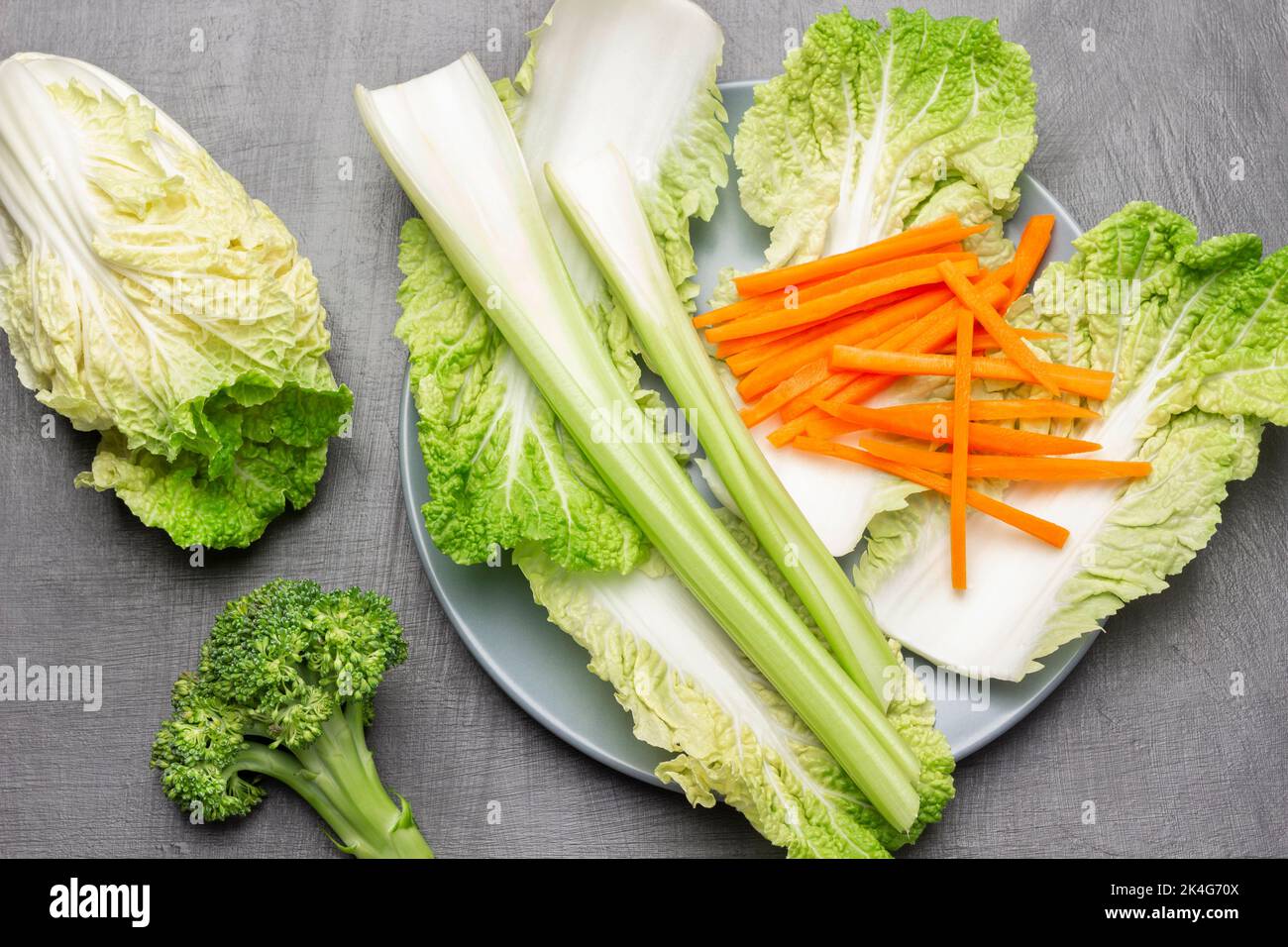 Cabbage leaves, celery stalks and sliced carrots on gray plate ...