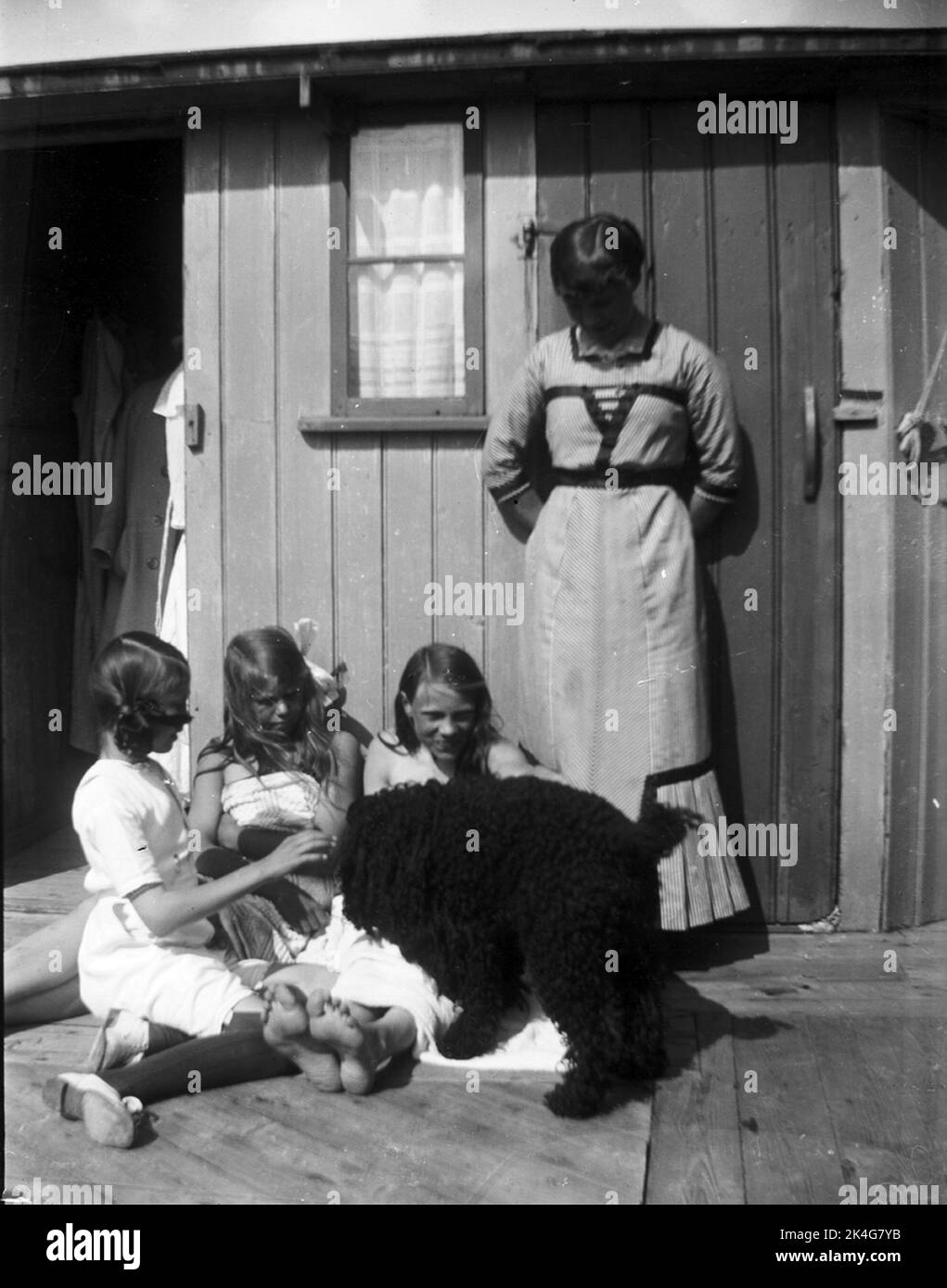 A woman looks at when three girls pat a dog. Nordic Stock Photo - Alamy