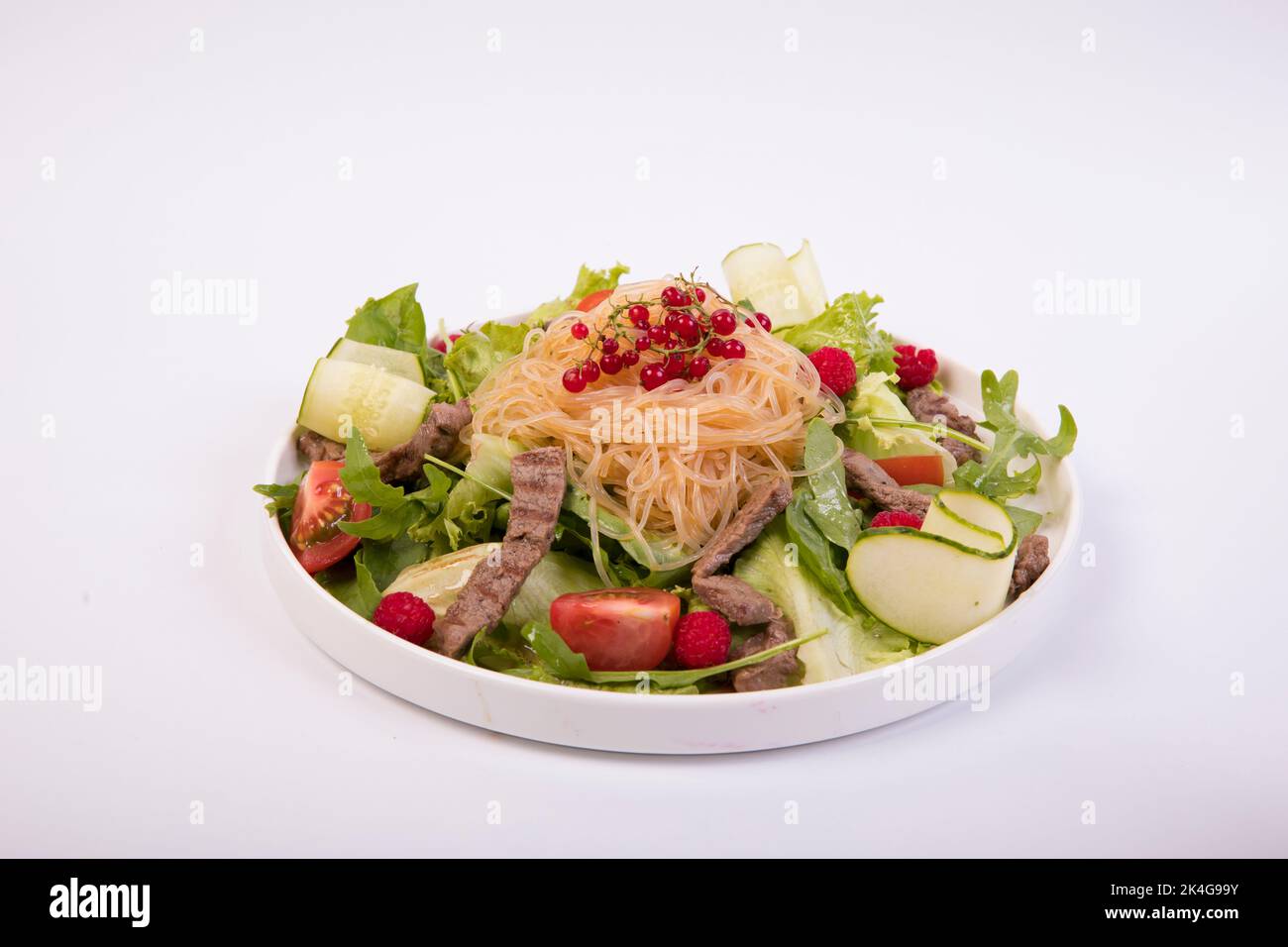 A closeup shot of spaghetti with vegetable salad isolated on a white ...