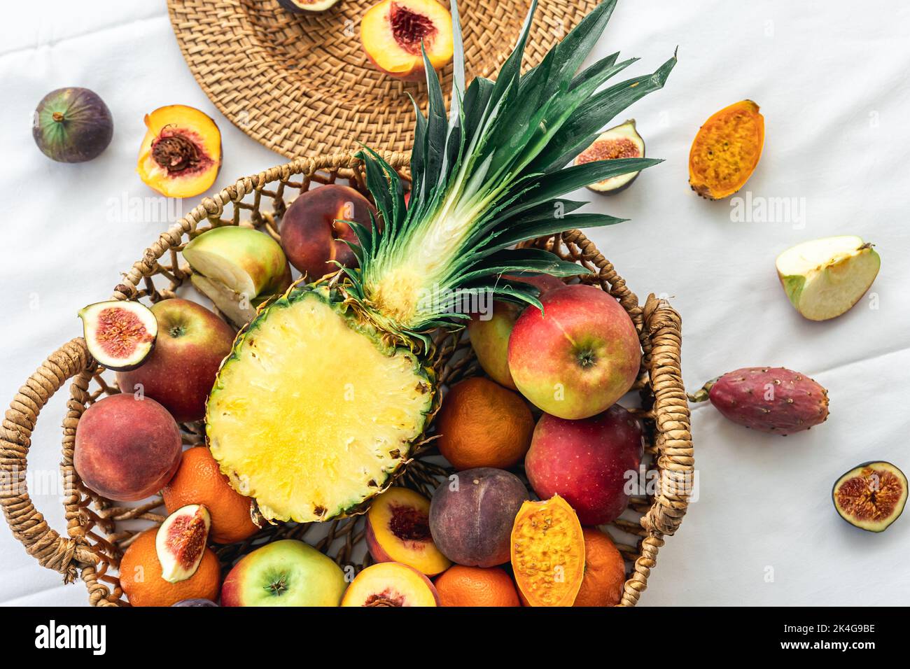Pineapple and other exotic fruits in a basket on a white background ...