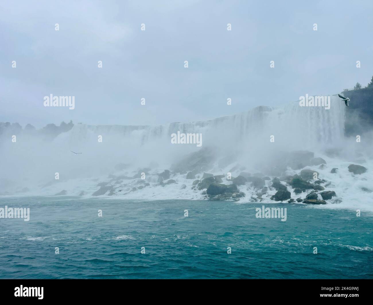 A scenic view of a waterfall crashing into rocks on a gloomy day Stock ...
