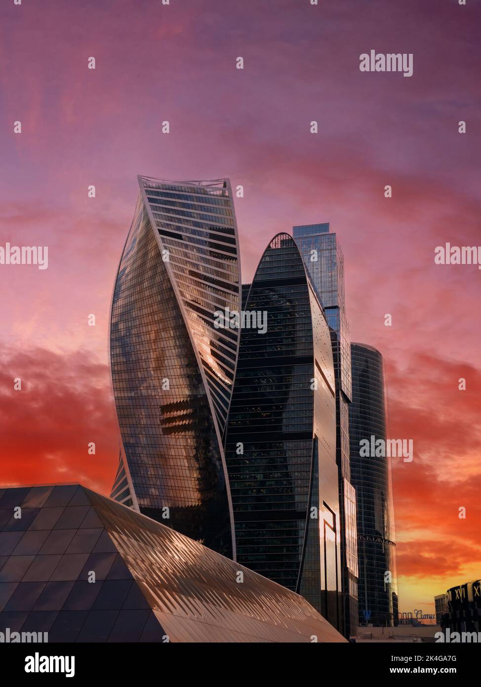 Tops of modern corporate buildings against the gloomy red sunset sky ...