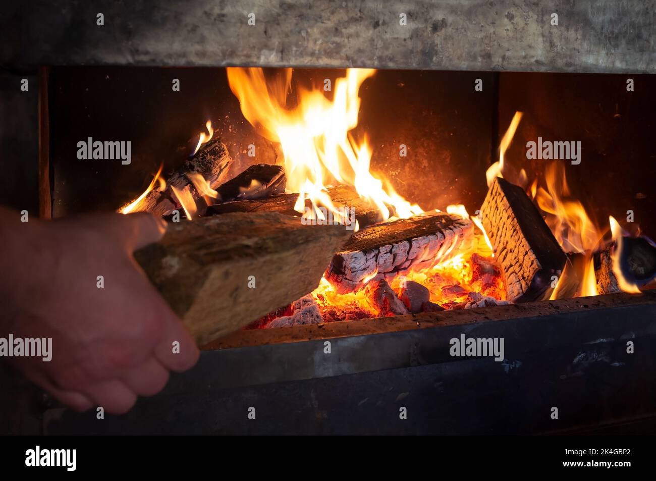 Hand puts a log on a fire to heat a home Stock Photo - Alamy