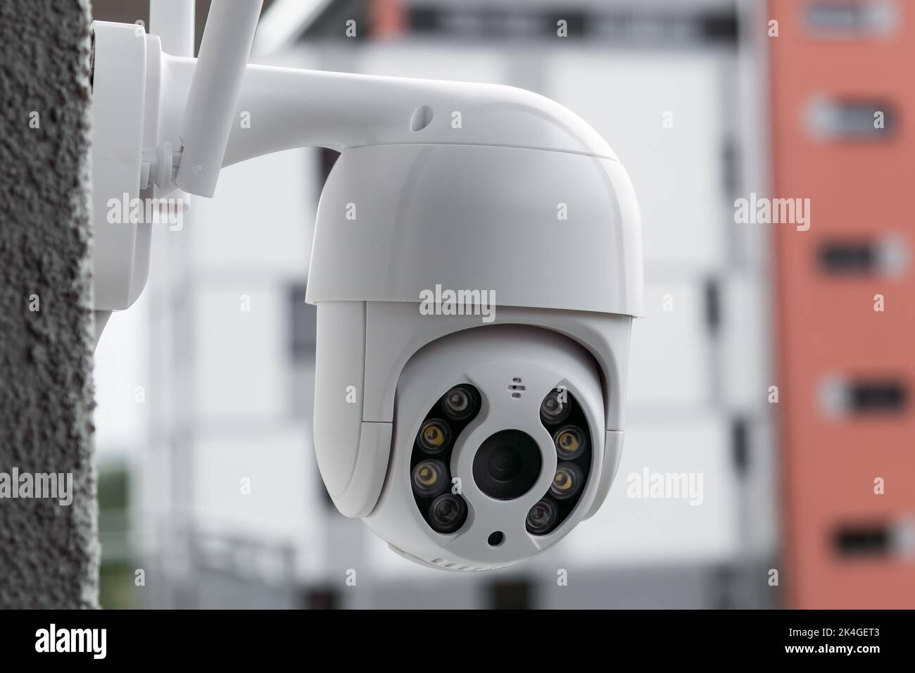 Modern CCTV camera on a wall with a blurred multi-storey building on ...