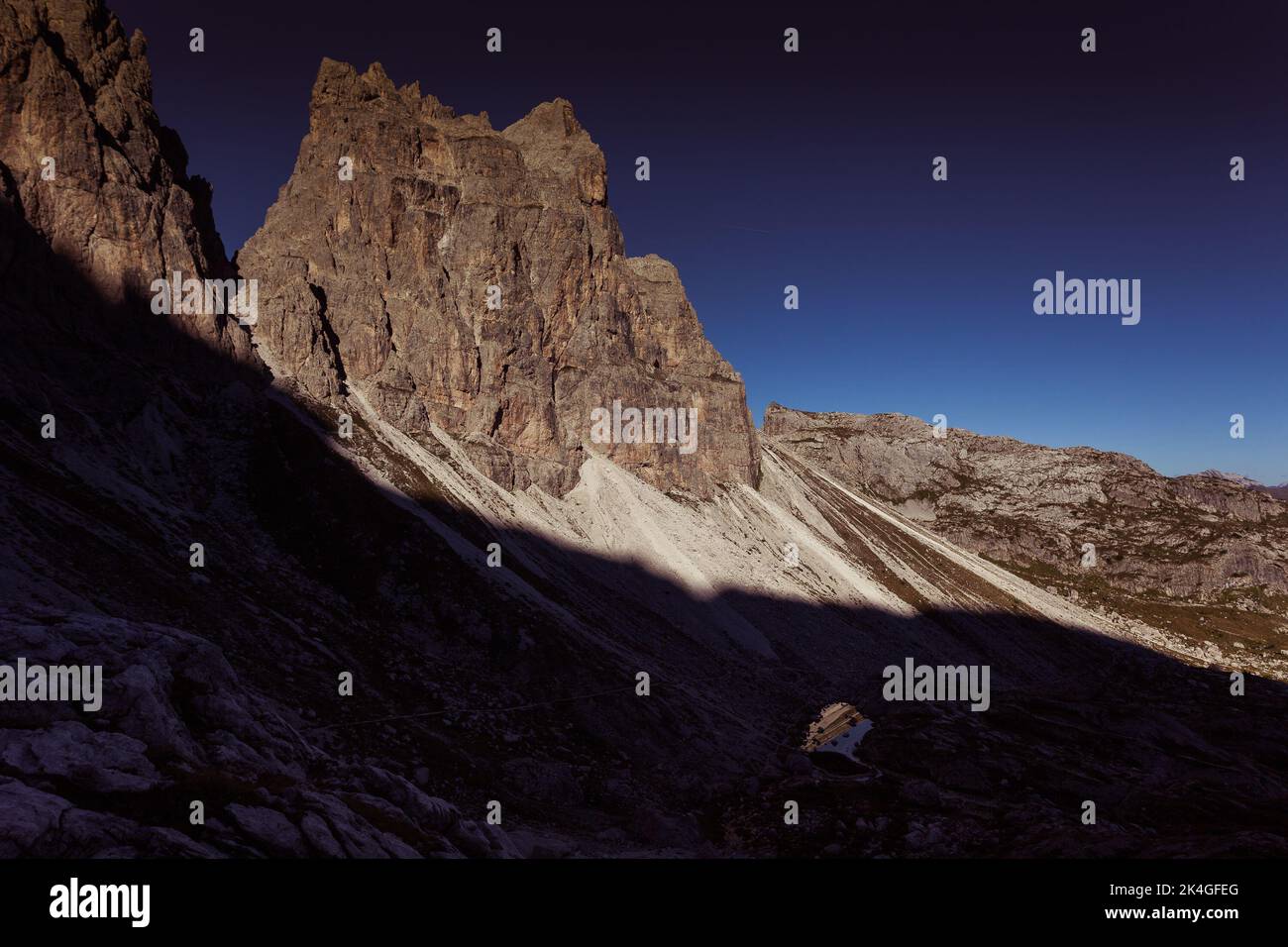 Lake at the foots of rocky ridges of Pala di Popera Mountain at evening ...