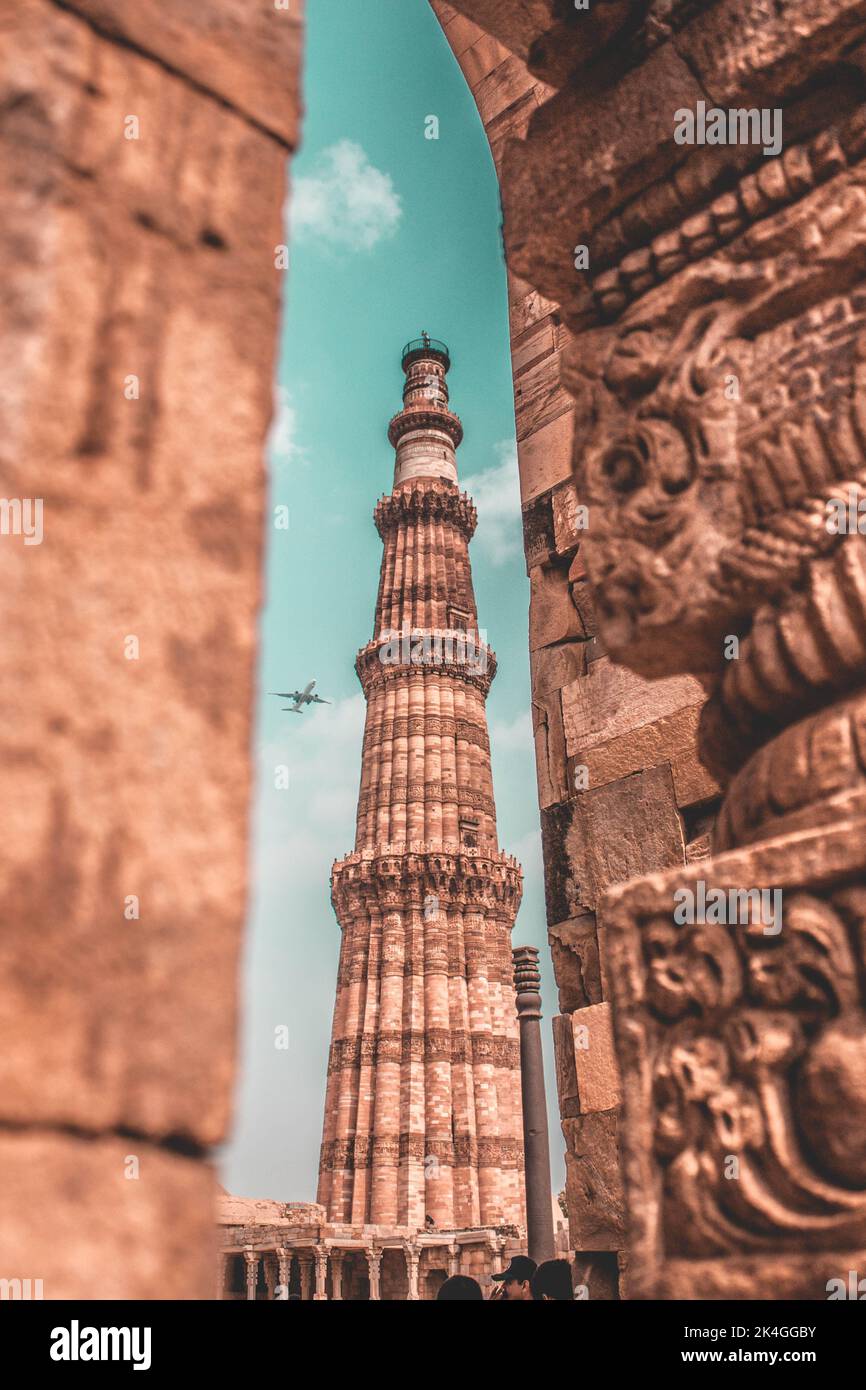 A vertical of the Iron Pillar monument and a plane in New Delhi, India ...