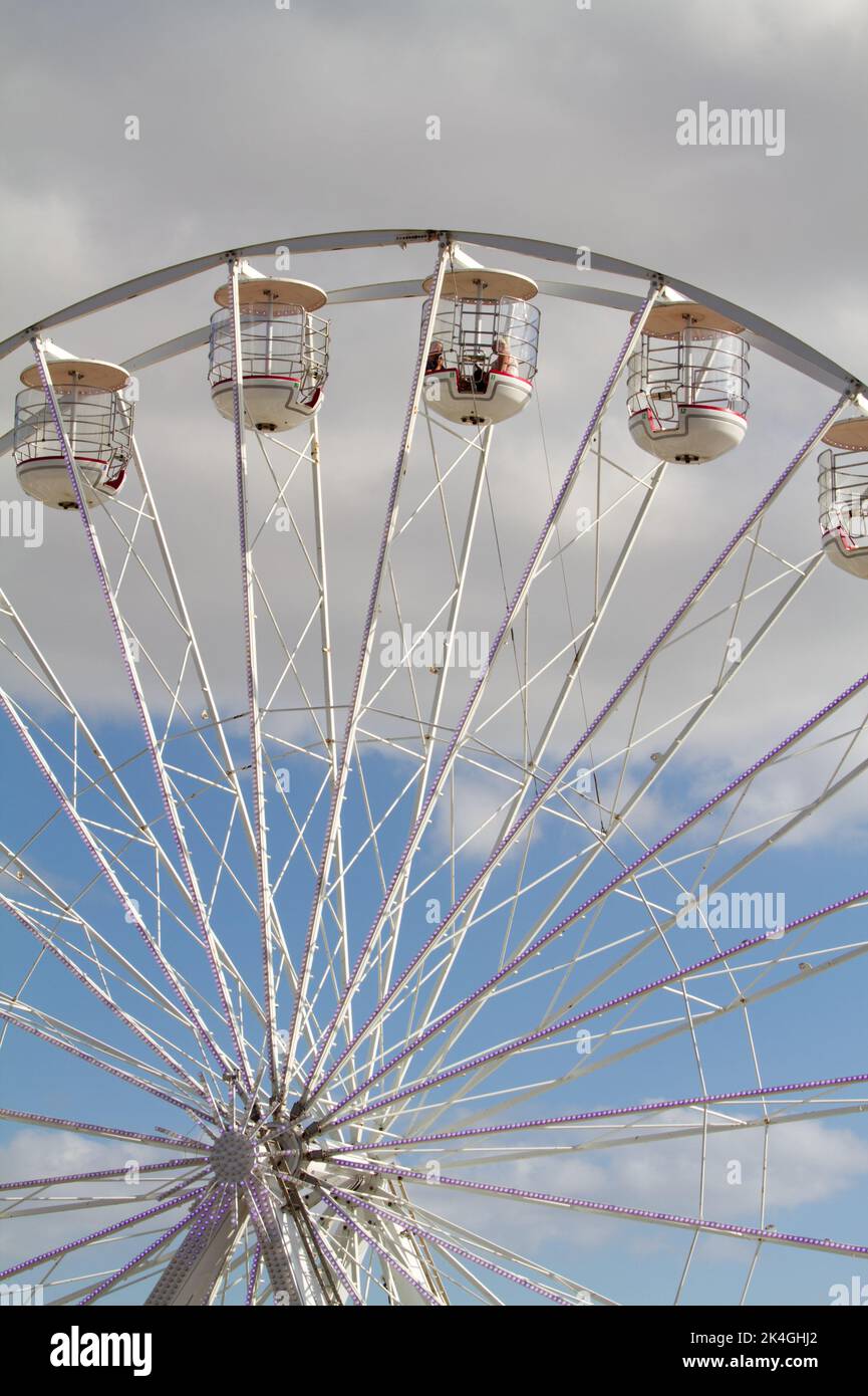 A section of a Ferris wheel with two people in one of the cabins at the ...