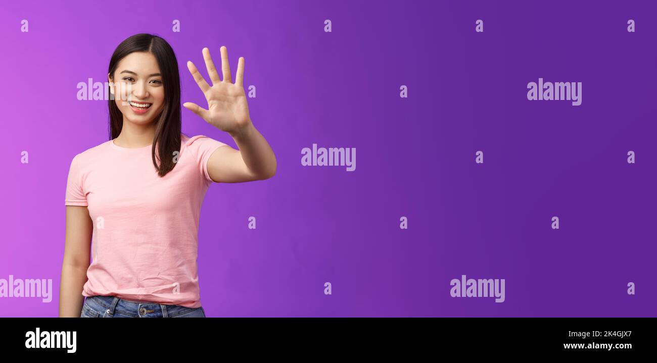 Friendly cute asian tender girl raise palm waving goodbye, smiling ...