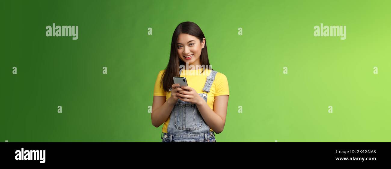 Cute tender asian gorgeous woman using smartphone, smiling carefree ...