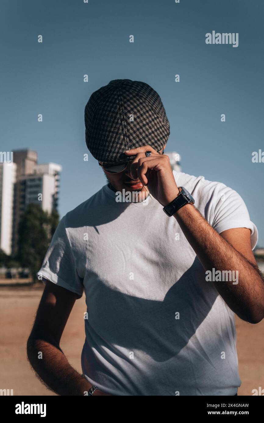 A vertical shot of a caucasian boy in a white t-shirt and sunglasses ...