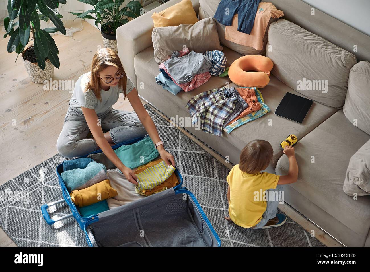 Mother and child are packing things in a suitcase together. Family ...