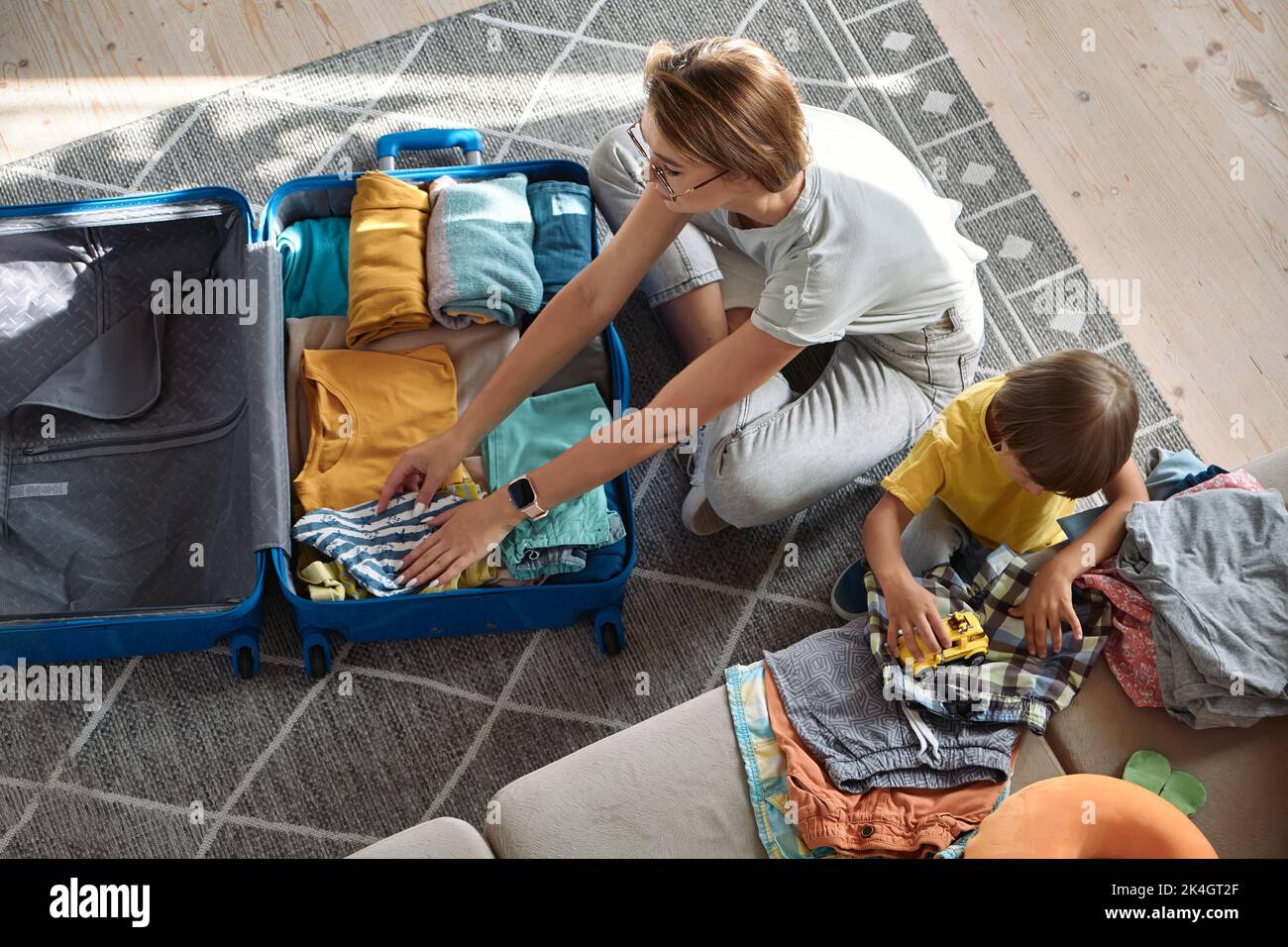 Mother and child are packing things in a suitcase together. Family ...