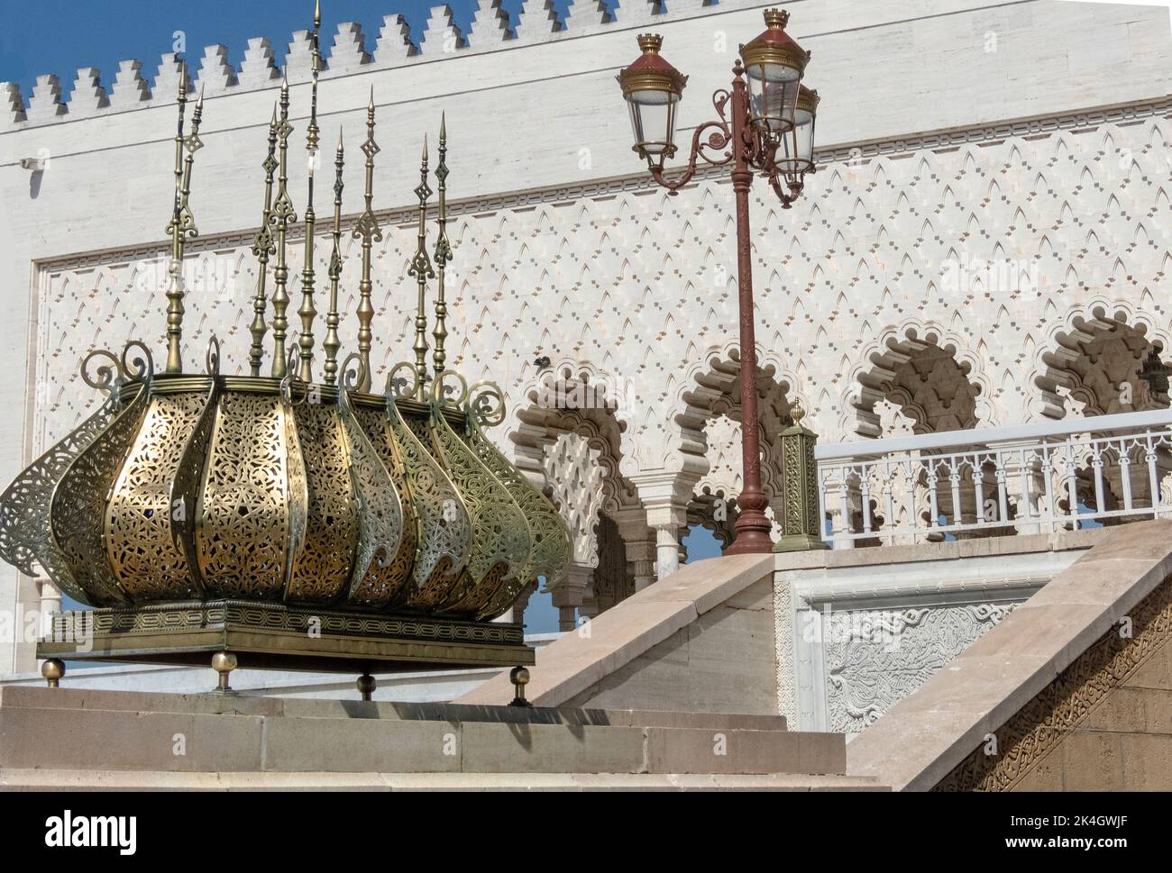 Brass urn and spikes against a white building and next to a ornate ...
