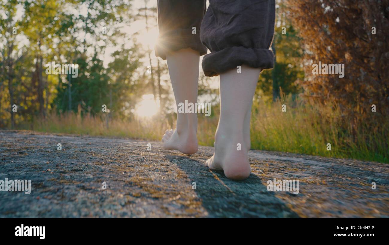 Barefoot legs of man walking through wild flowers and moss on sunny day ...