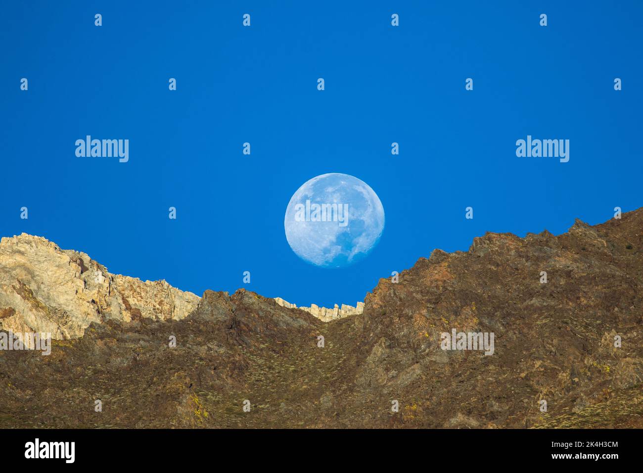 Full moon setting behind a mountain ridge in the Sierra Nevada ...