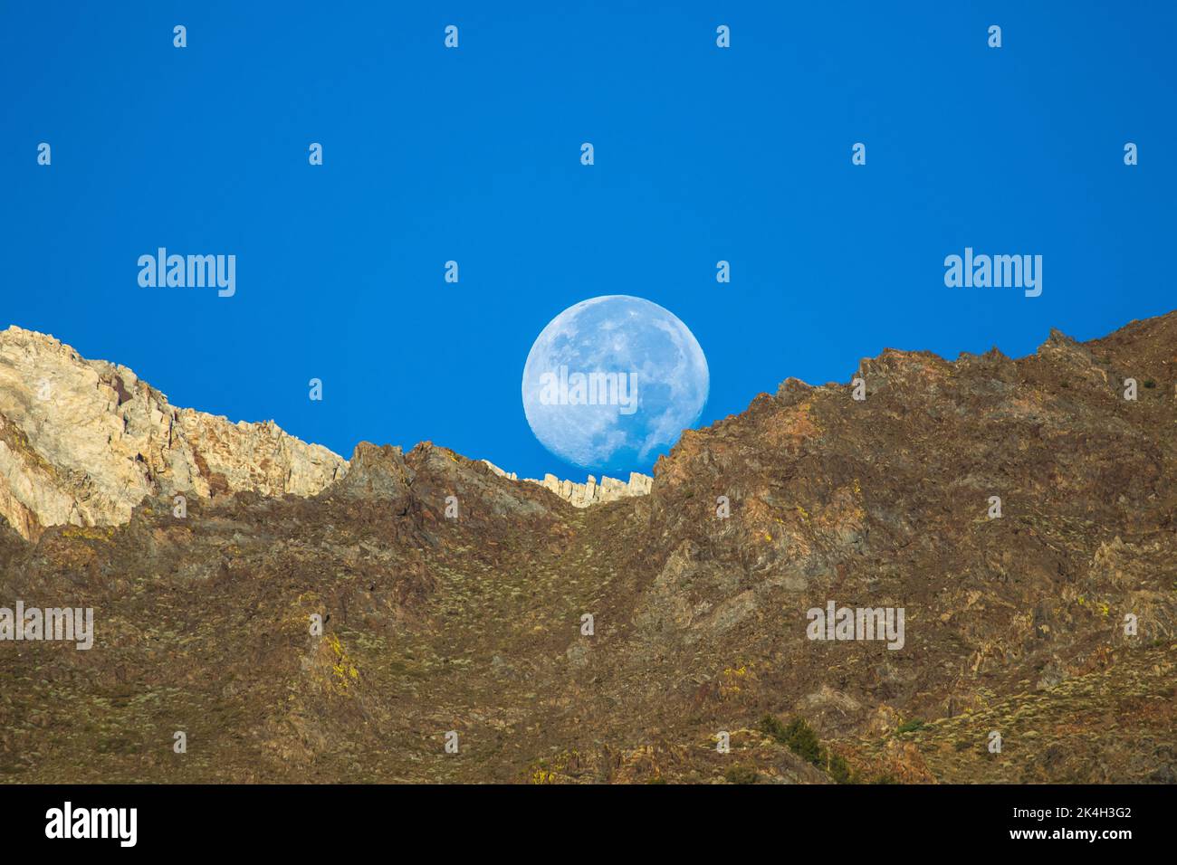 Full moon setting behind a mountain ridge in the Sierra Nevada ...