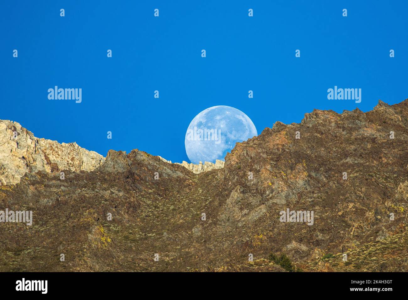 Full moon setting behind a mountain ridge in the Sierra Nevada ...