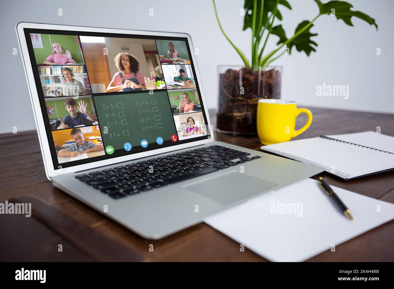 Smiling diverse elementary school pupils waving during class on laptop ...