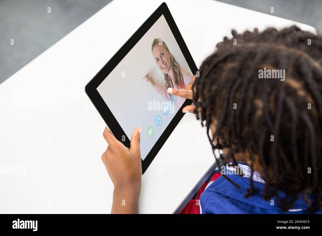 Male student having a video call with female teacher on digital tablet ...