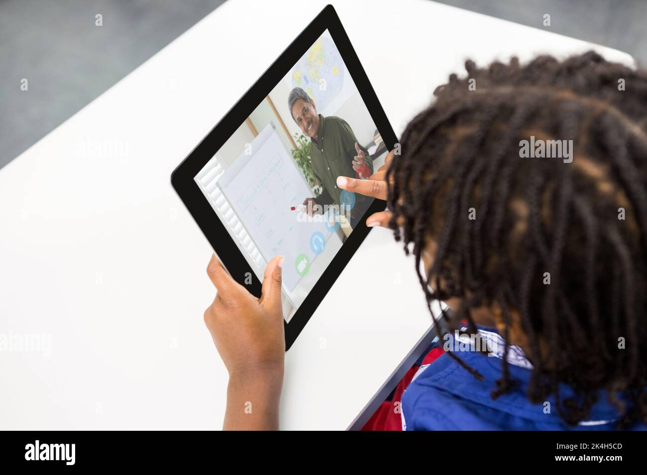 Male student having a video call with male teacher on digital tablet at ...