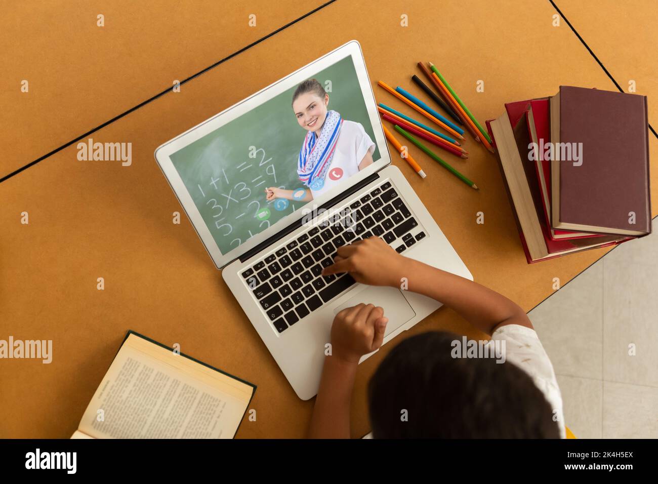 Overhead view of male student having a videocall with female teacher on ...