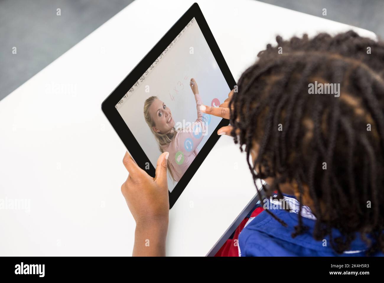 Male student having a video call with female teacher on digital tablet ...
