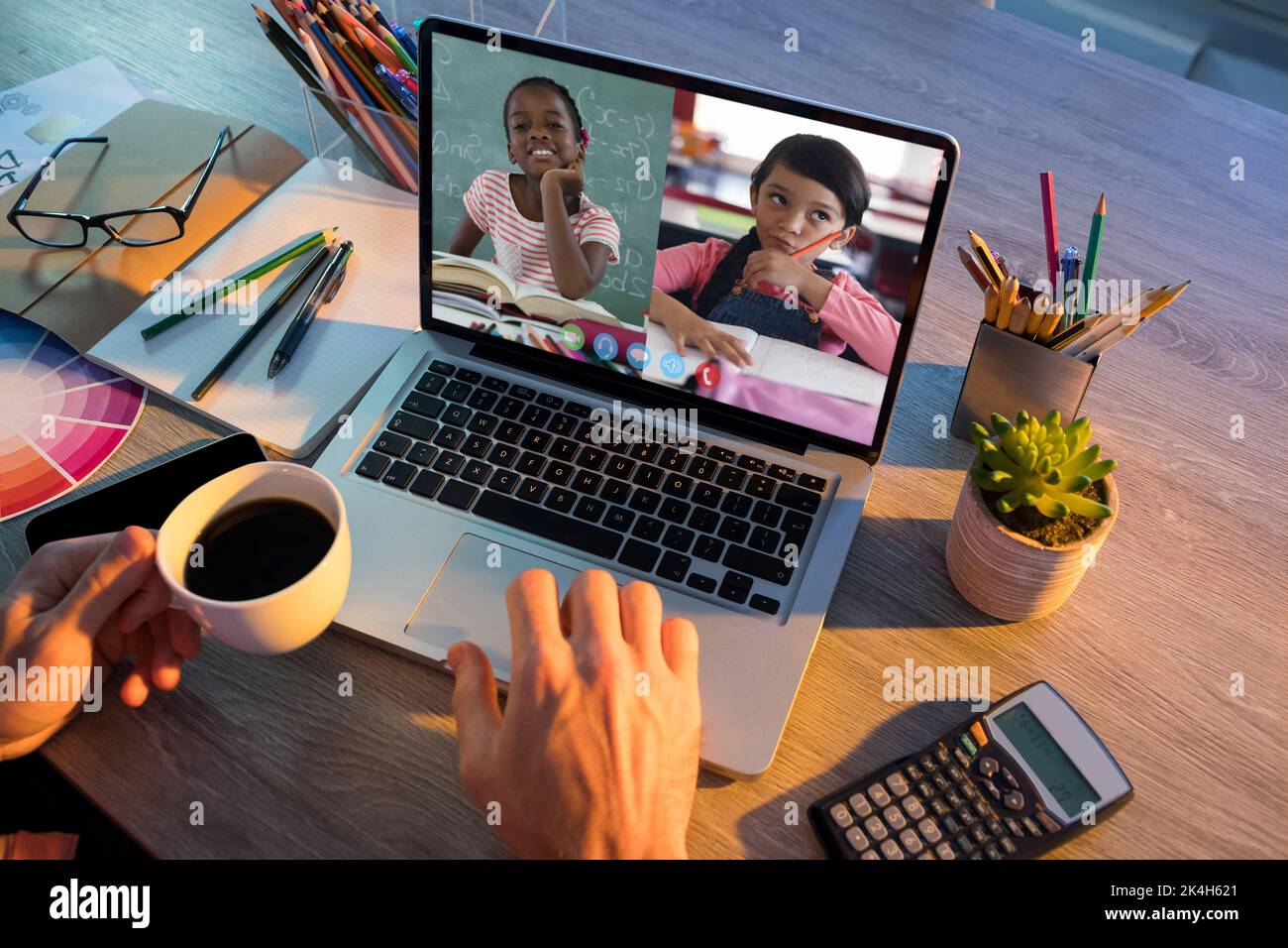 Mid section of teacher having a video conference with two female ...