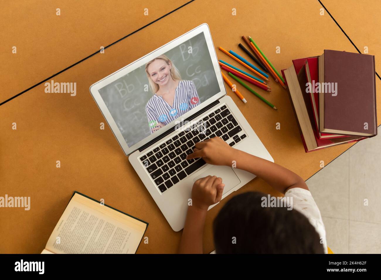 Overhead view of male student having a video call with female teacher ...