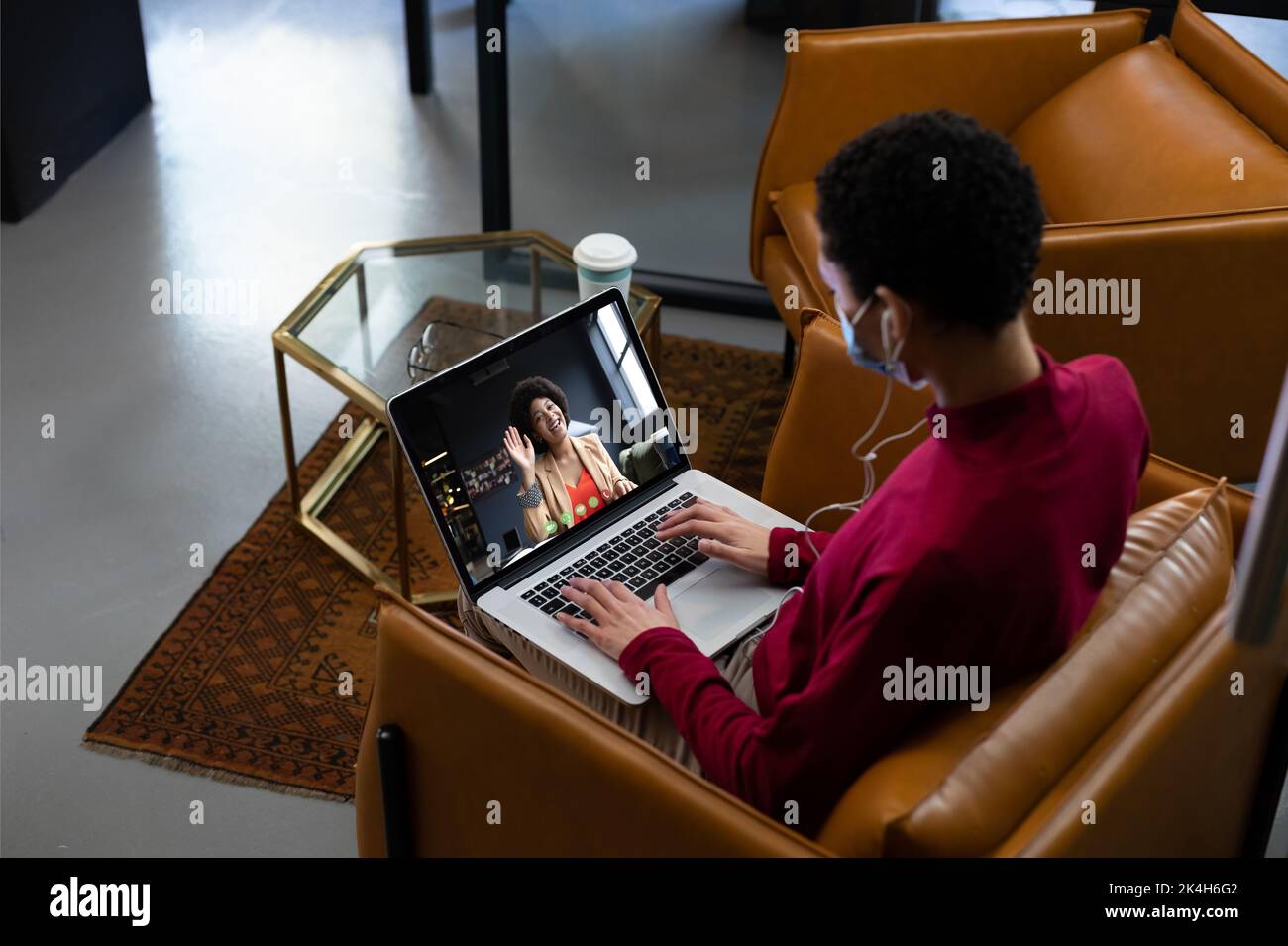 African american woman wearing face mask having video call with female ...