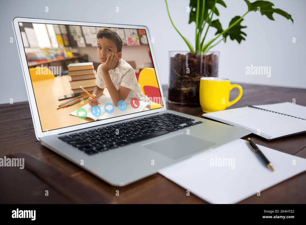 Mixed race schoolboy learning displayed on laptop screen placed on desk ...