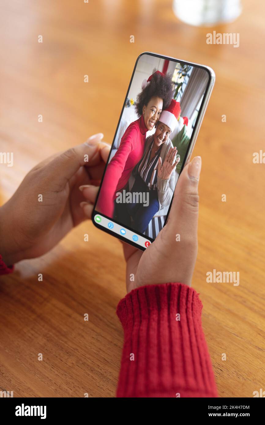 Hands holding smartphone with happy mother and daughter in christmas ...