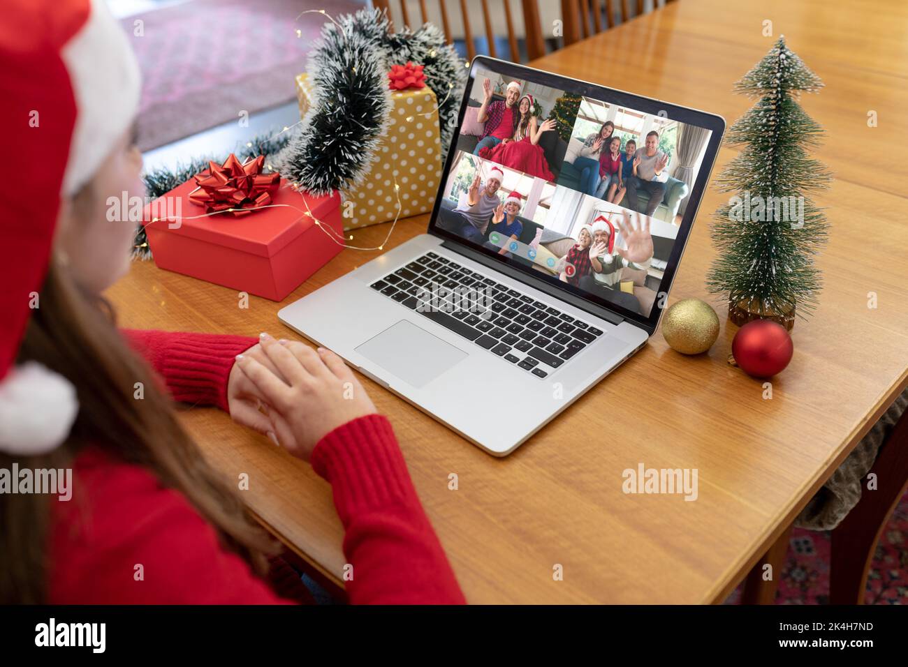 Caucasian woman in santa hat making christmas laptop group video call with family and friends ...