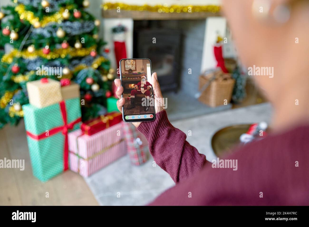 Woman making smartphone christmas video call with santa claus in face ...