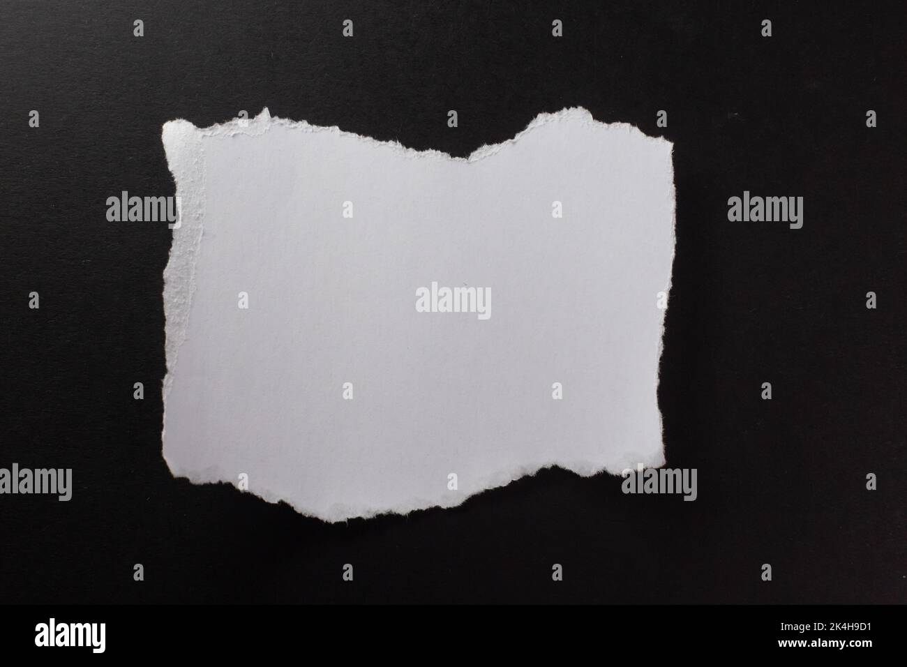 Roughly torn rectangle of white paper on black background. monochrome ...