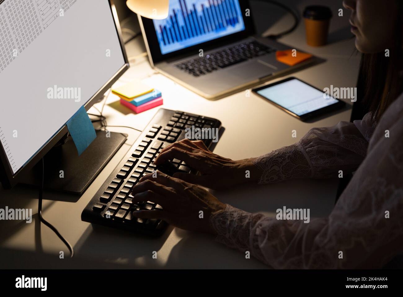 Hands of biracial female programmer sitting at desk, using computer with coding on screen ...
