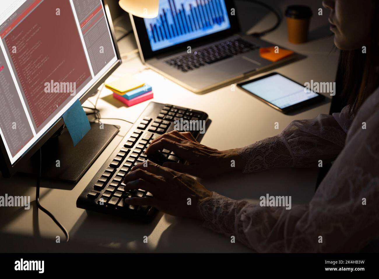 Biracial female programmer sitting at desk, using computer with coding on screen. coding ...