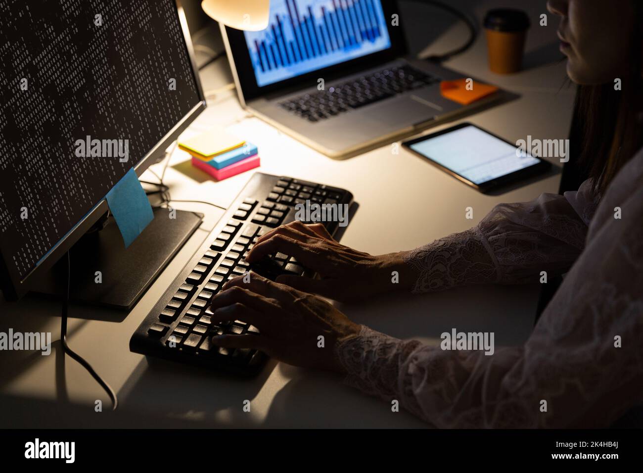 Hands of biracial female programmer sitting at desk, using computer with coding on screen ...