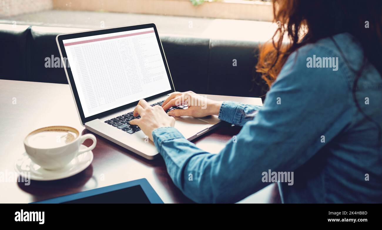 Caucasian female programmer sitting at desk with coffee, using laptop ...