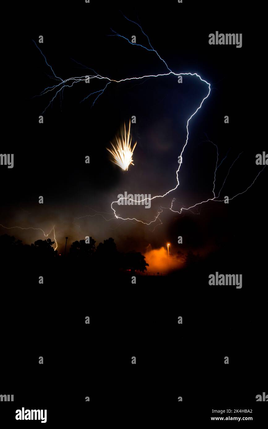 A vertical shot of flying sparks and striking lightning in a night sky ...