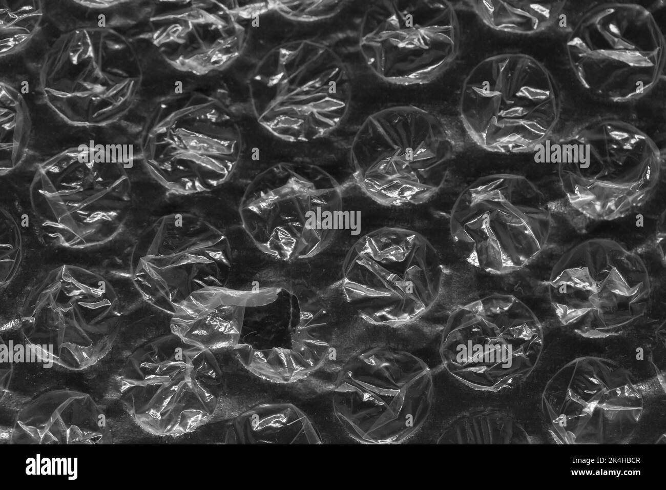 Reflecting light and shadow on creases and tears in plastic bubble wrap ...