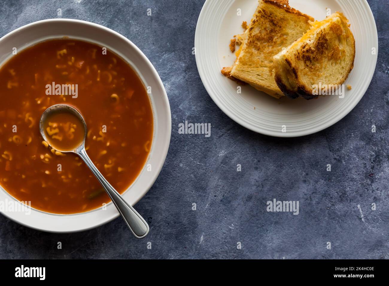 Top down view of a bowl of alphabet soup served with a grilled cheese ...