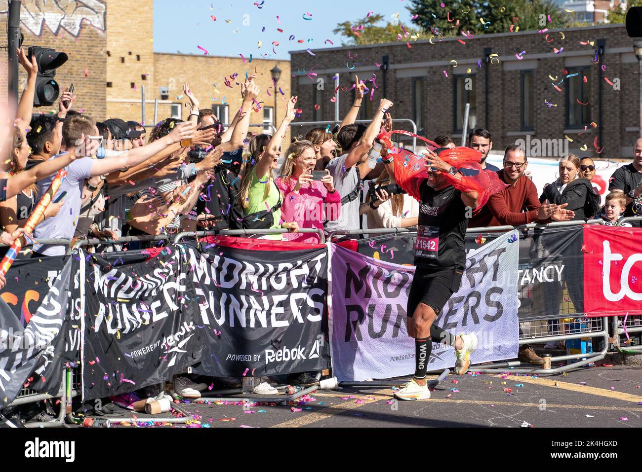 A runner seen showered in confetti at a supporter cheer zone with ...