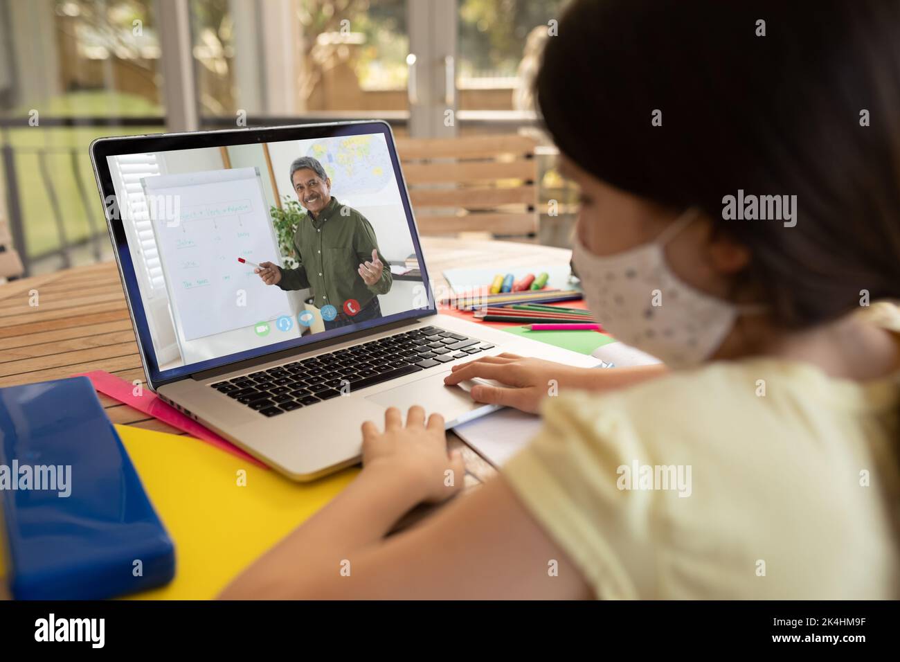 Female student wearing face mask having a video call with male teacher ...
