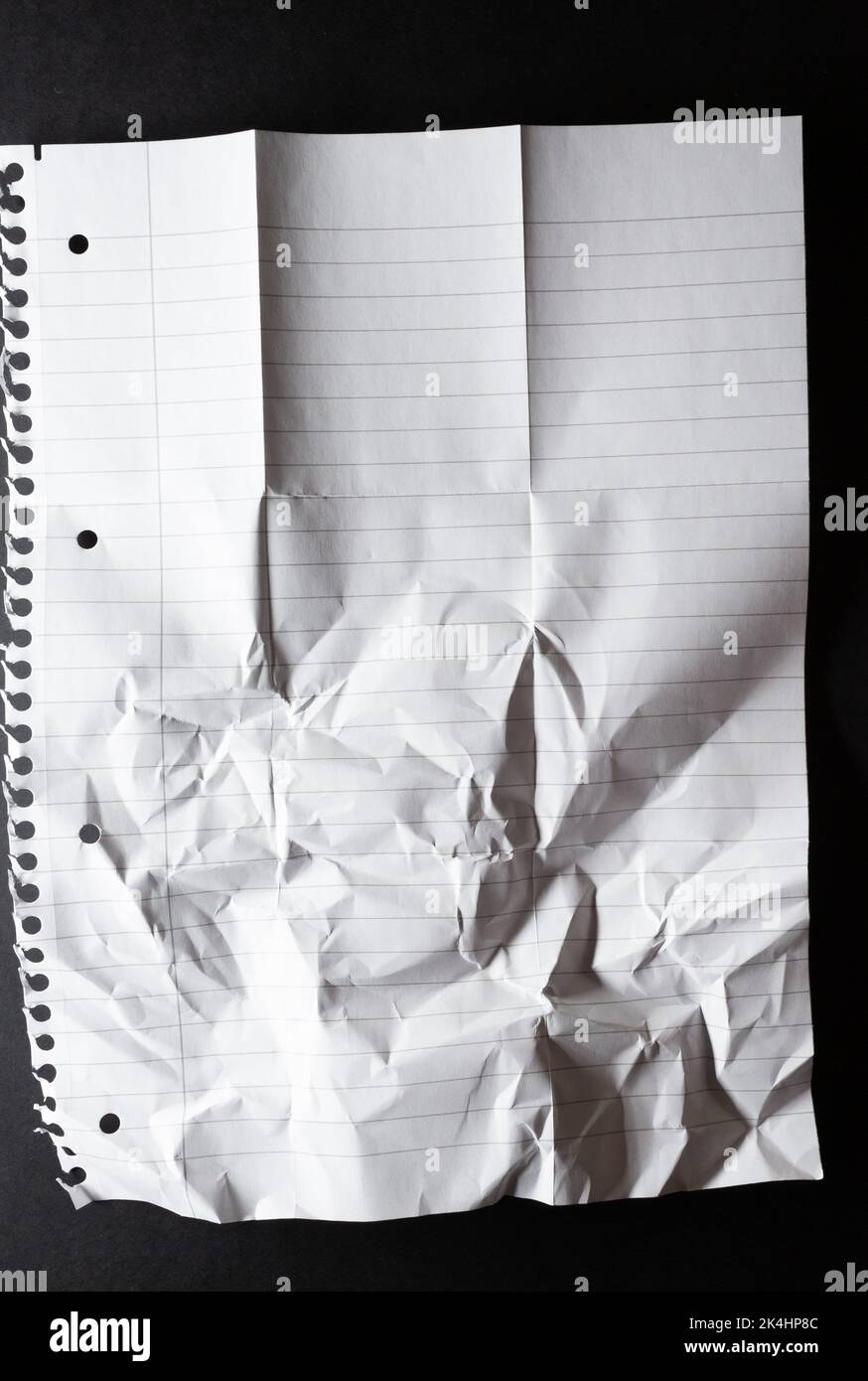 Hole punched sheet of lined paper, torn from spiral binding, folded and ...