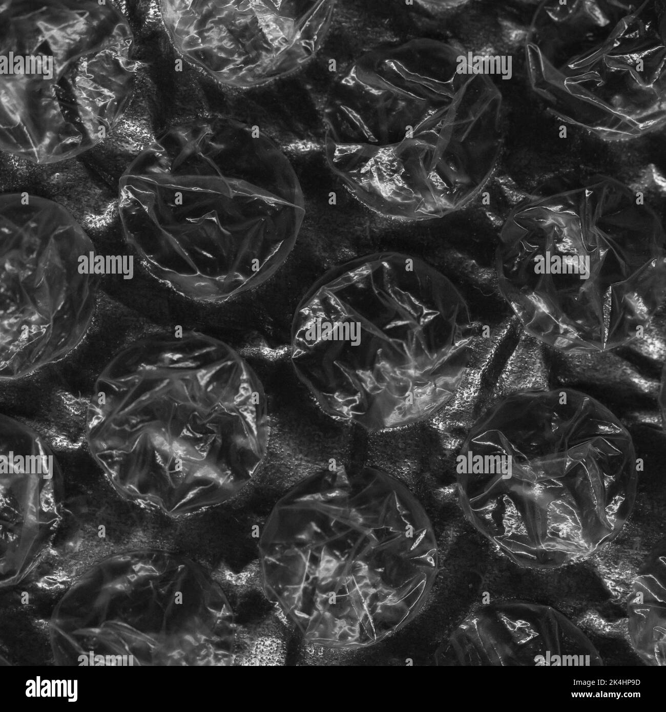 Close up of reflecting light and shadow on creases and tears in plastic ...