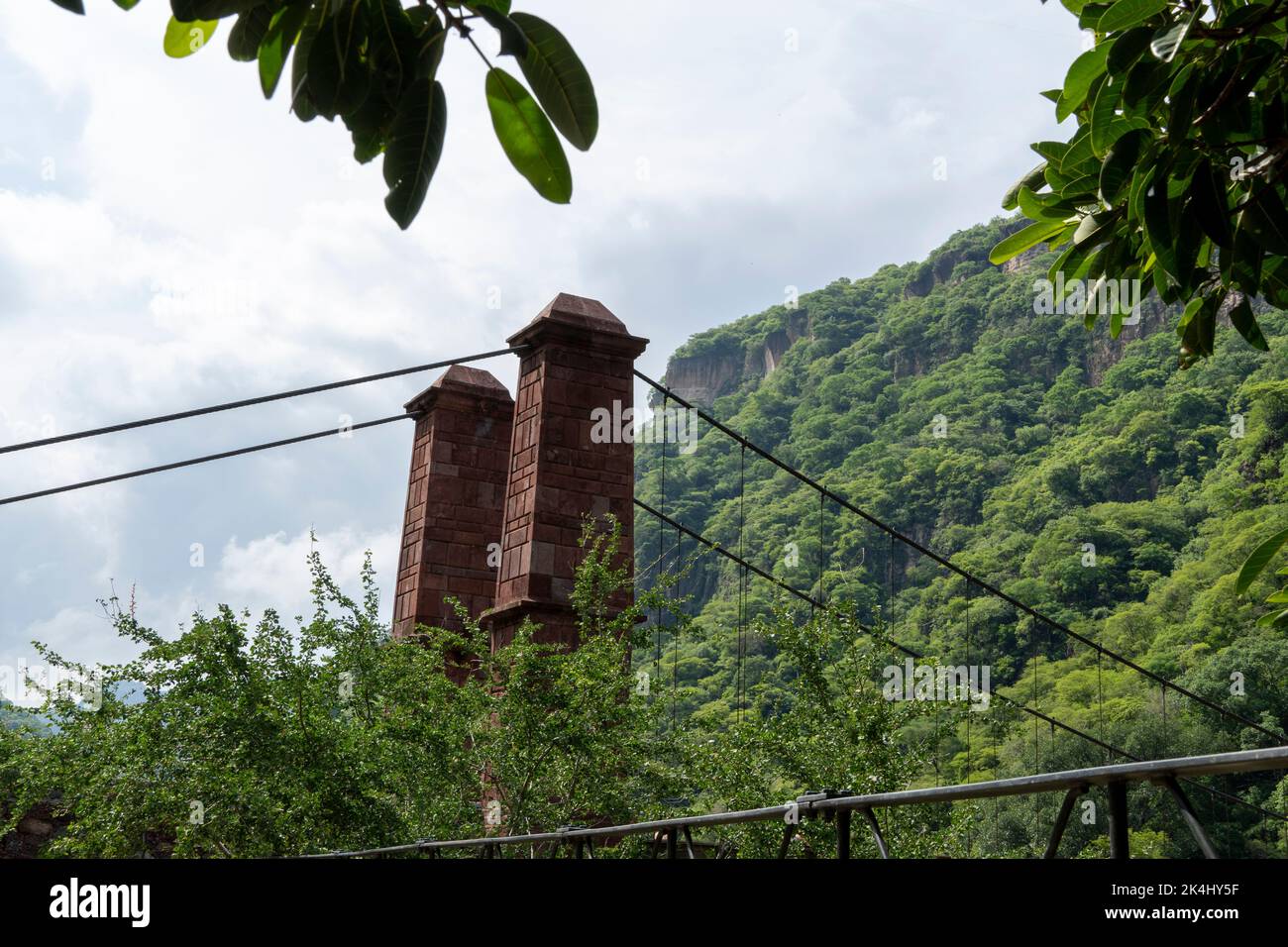 rusty cable, river and mountain in the background, vegetation barranca ...