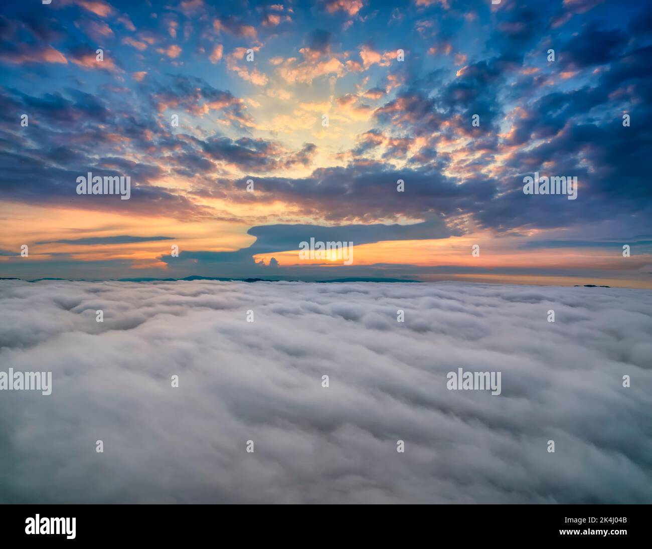 Aerial view of colorful sunrise over white dense fog with distant dark ...