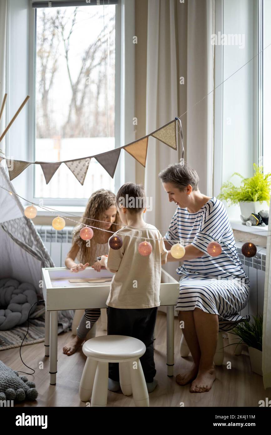 Mother explaining children early development sensory sandbox tasks ...